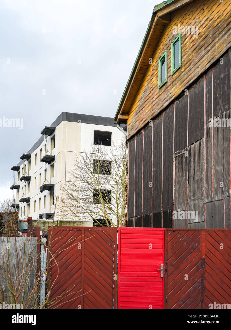 Juxtaposition of traditional wooden house and modern concrete apartment ...