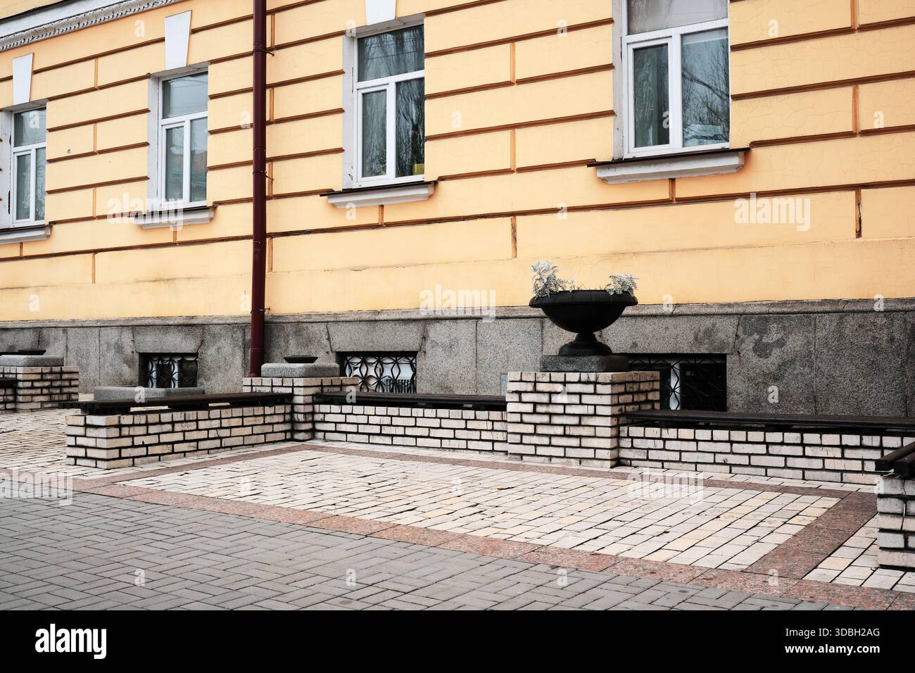 A quiet city corner features soft yellow walls and neat, inviting brick ...