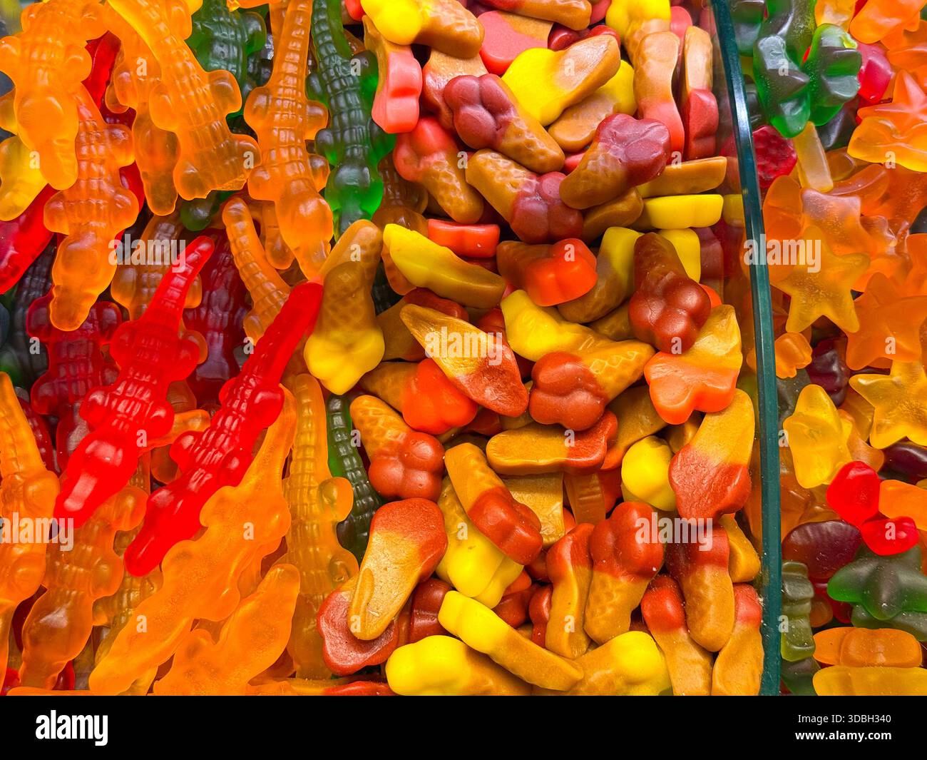 Colorful gummy candies shaped as playful figures densely packed in a ...