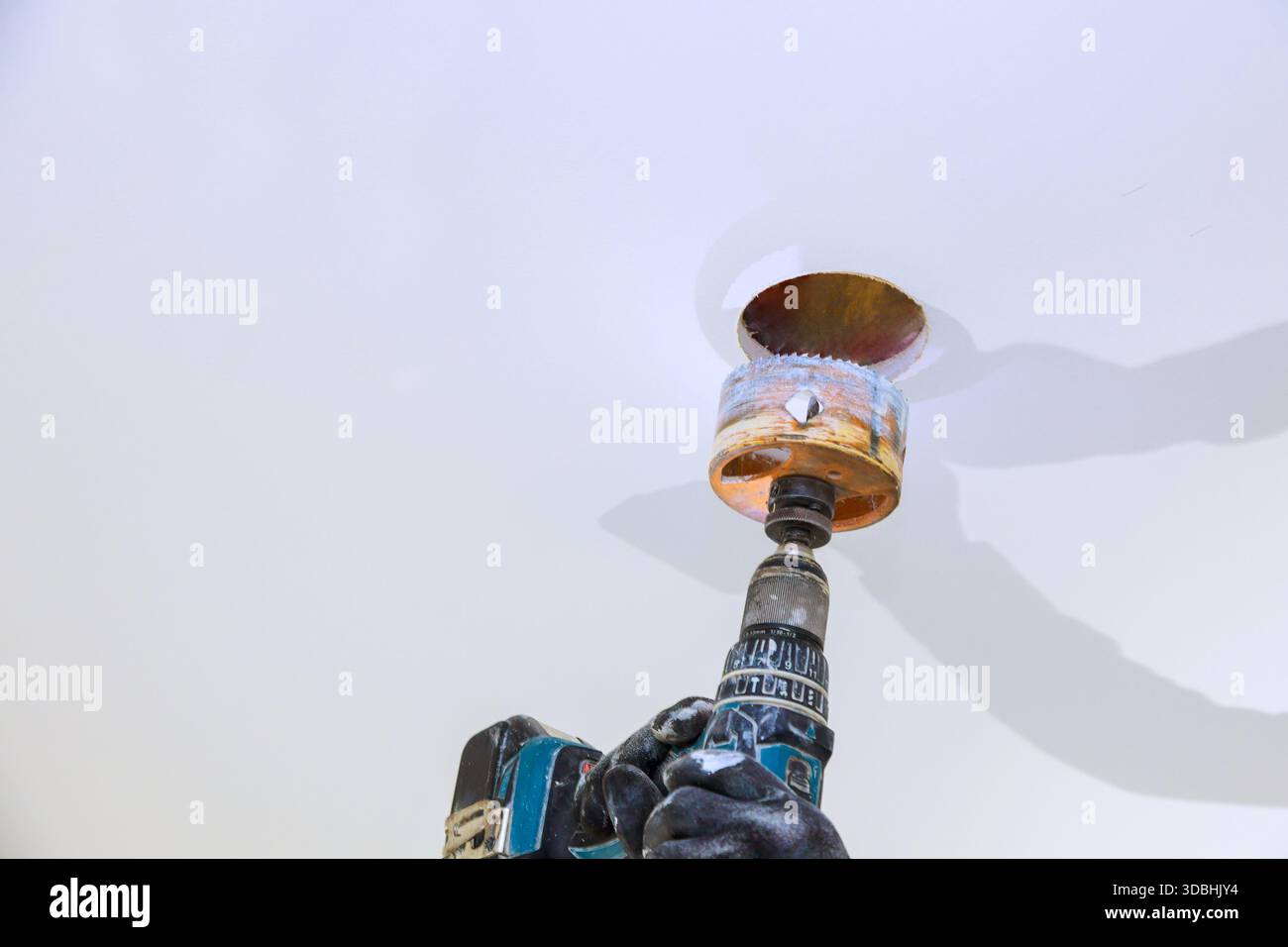 Worker is using drill to create hole in the ceiling during renovation ...