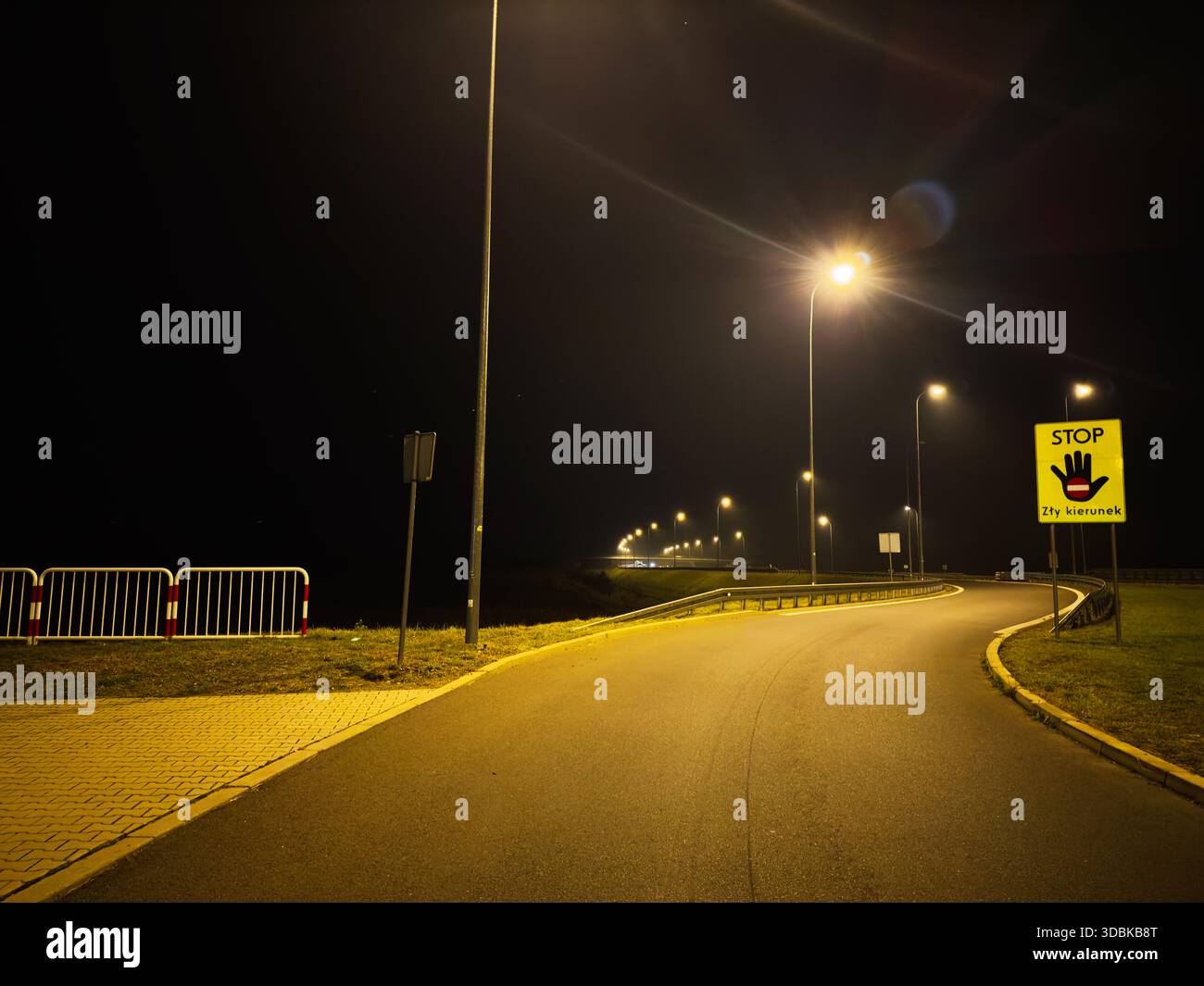 Quiet night road with bright streetlights, a gentle curve, and a stop ...