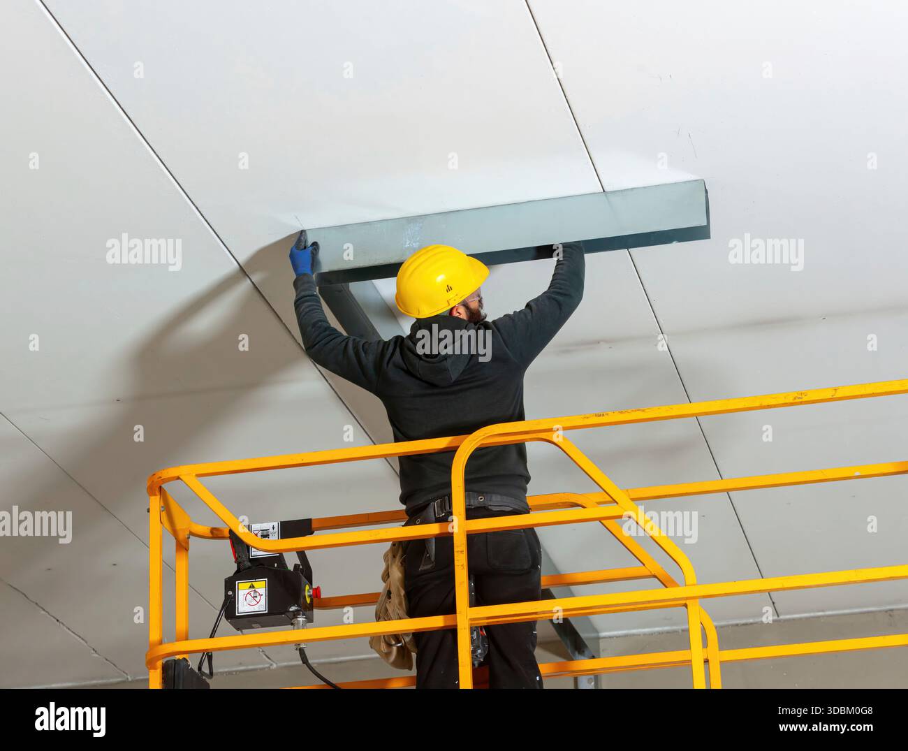 Construction worker on aerial work platform installing metal profile ...