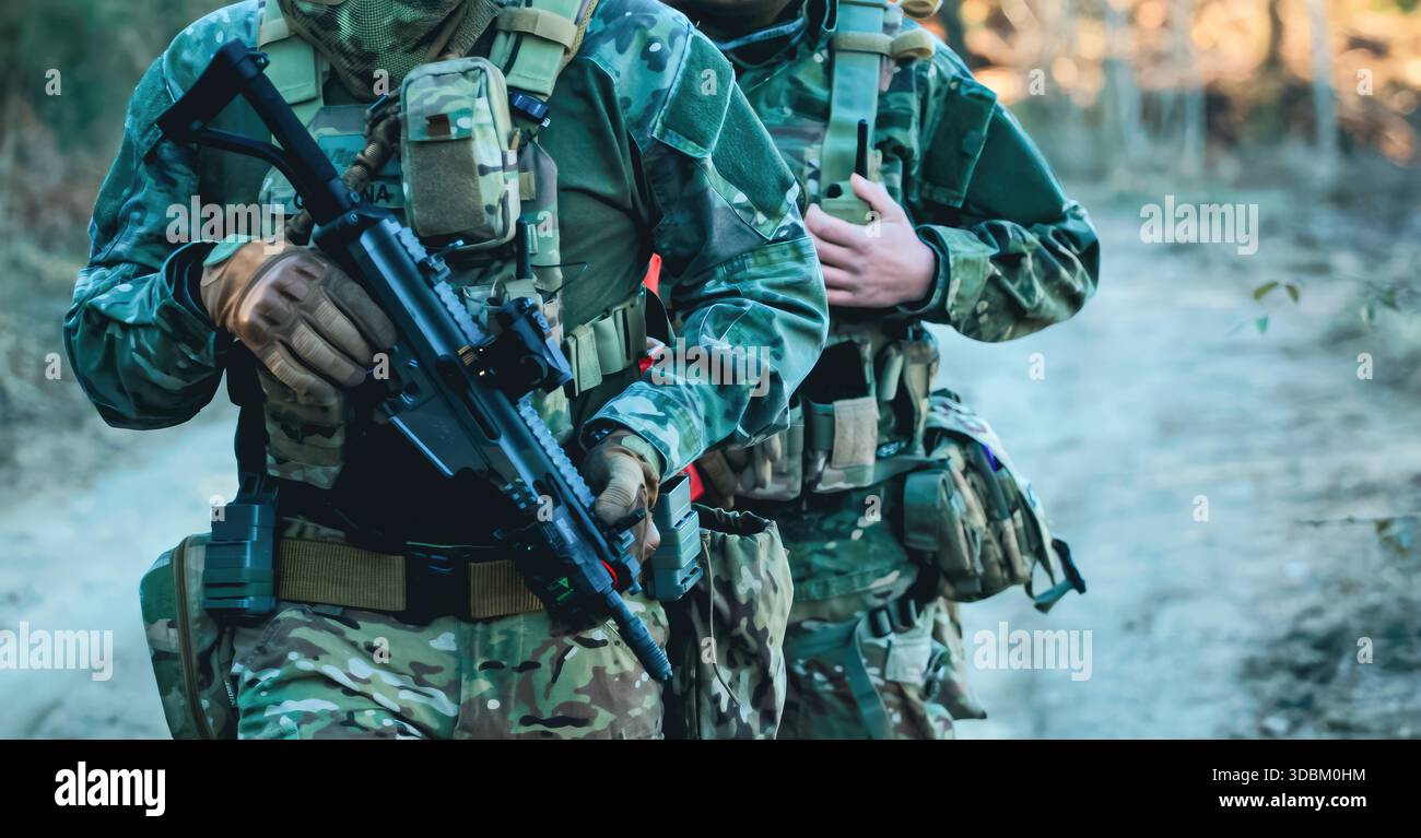 Two soldiers patrolling through the dense forest, one gripping a rifle ...
