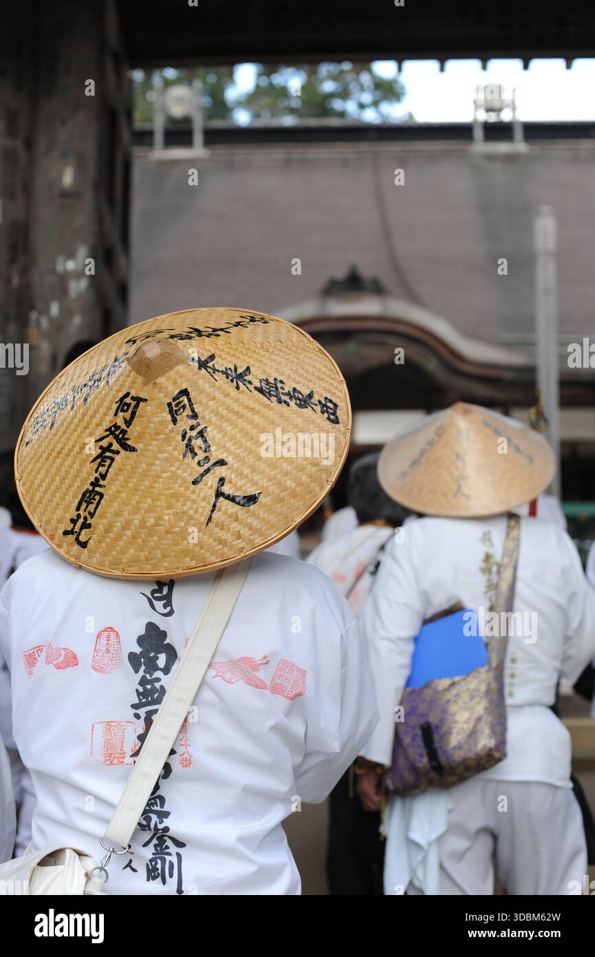 Pilgrims in straw Buddhist hats entering a sacred Buddhist site of ...