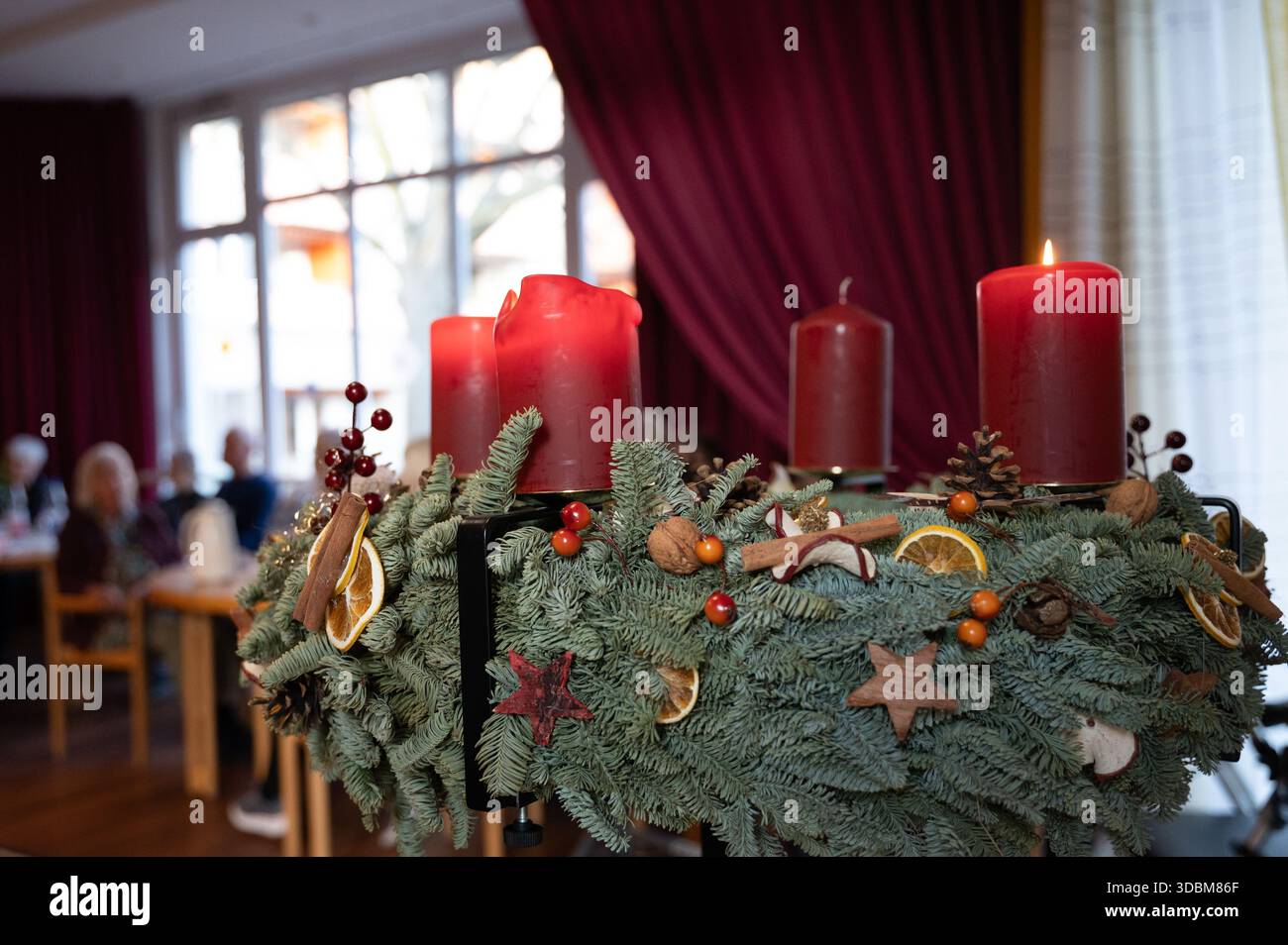 16 December 2025, Berlin: An Advent wreath decorated with fir branches ...