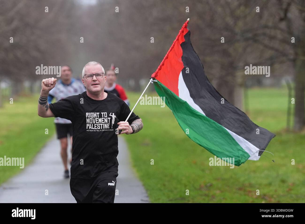 A man carries a Palestinian flag during a 10K charity run with Kneecap ...