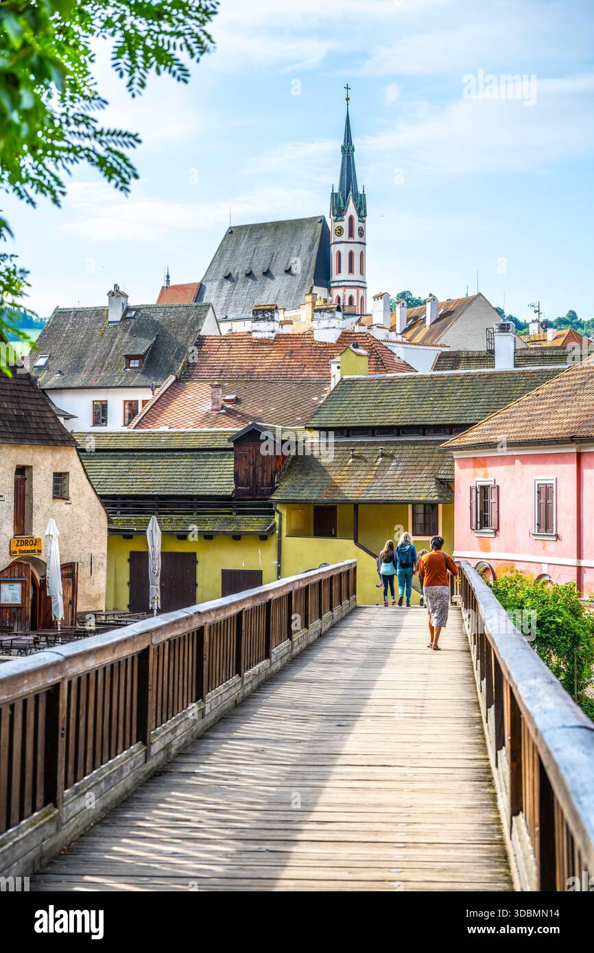 Visitors stroll along a wooden bridge in Cesky Krumlov. The historical ...
