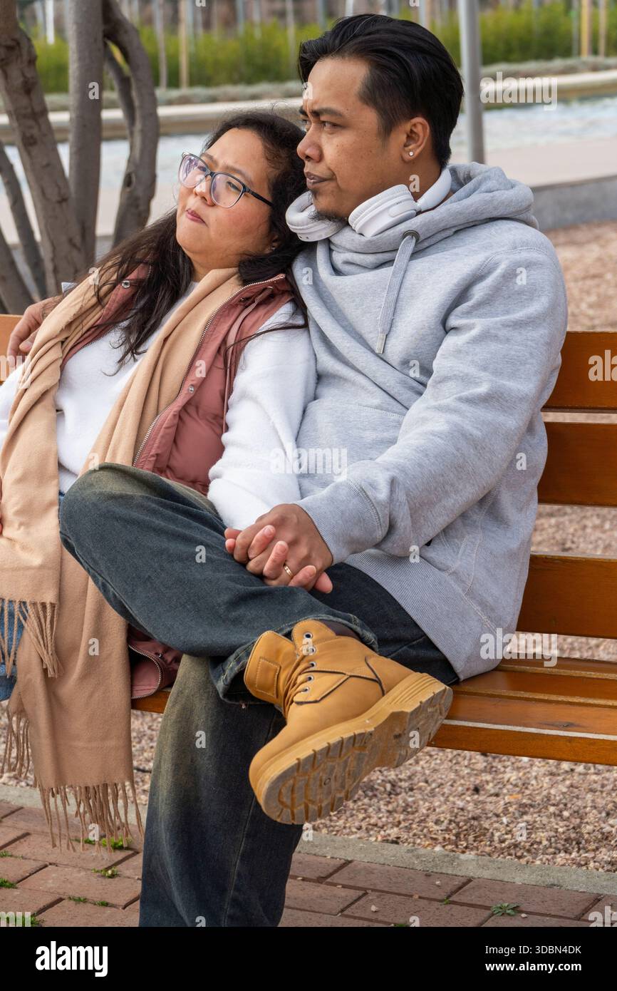 Nostalgic Asian Filipino couple relaxing together on park bench ...