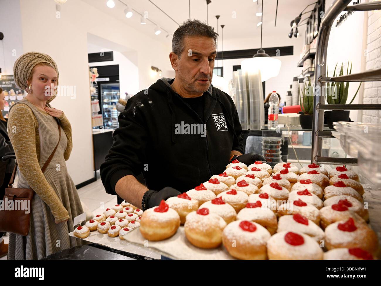 A baker carries a tray of donuts, sufganiyot, filled with jelly on the ...