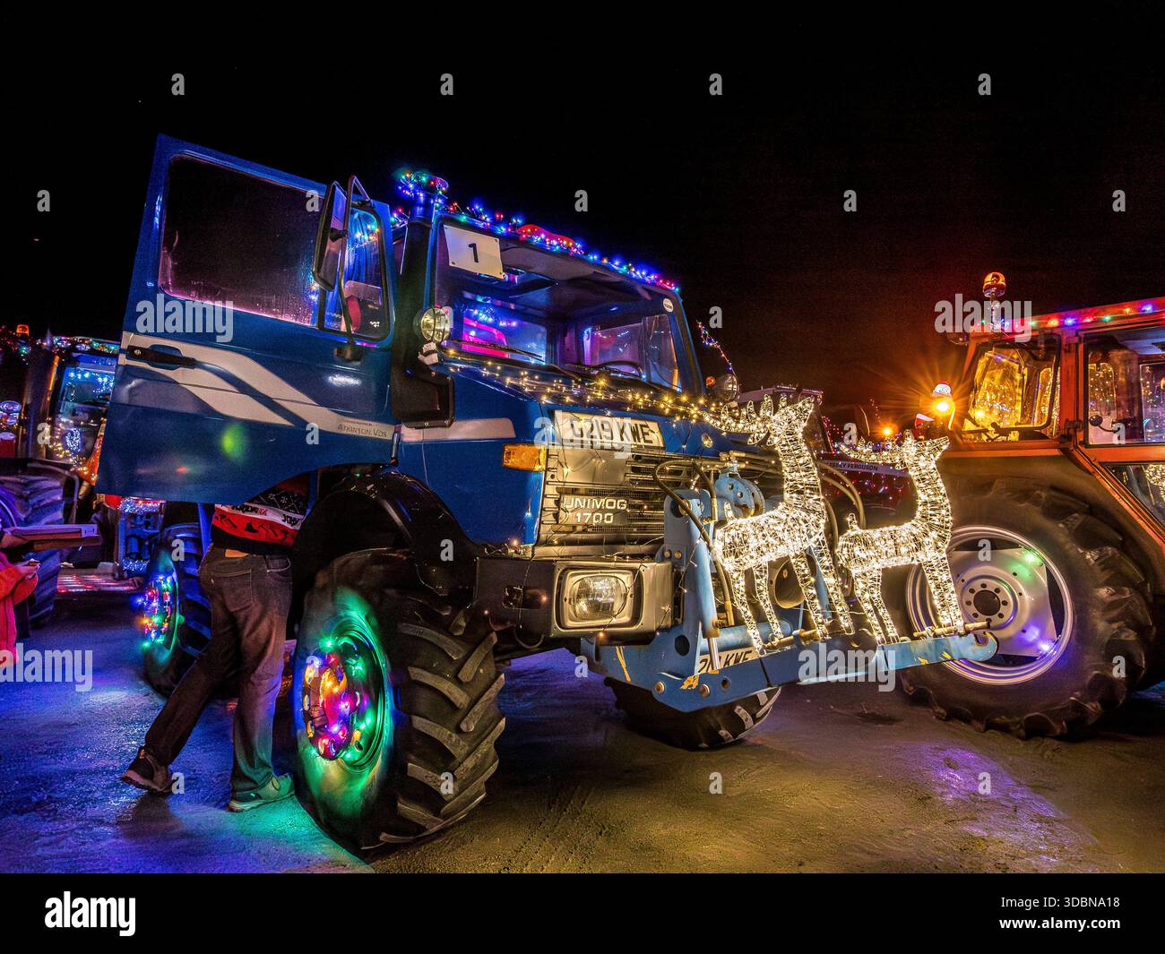 The image is of highly decorated farm tractors illuminated by lots of ...