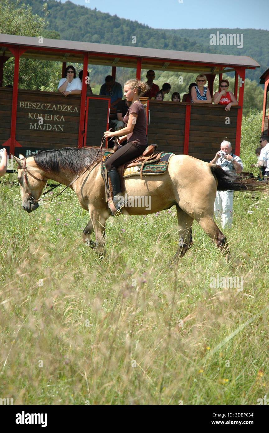 Tourist riding horse next to Bieszczadzka Kolejka Leśna after staged ...