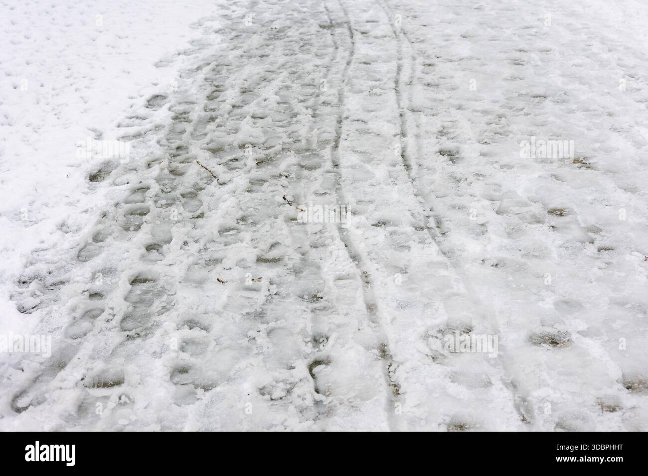 People walk along a snowy path leaving marks on the fresh snow in a ...