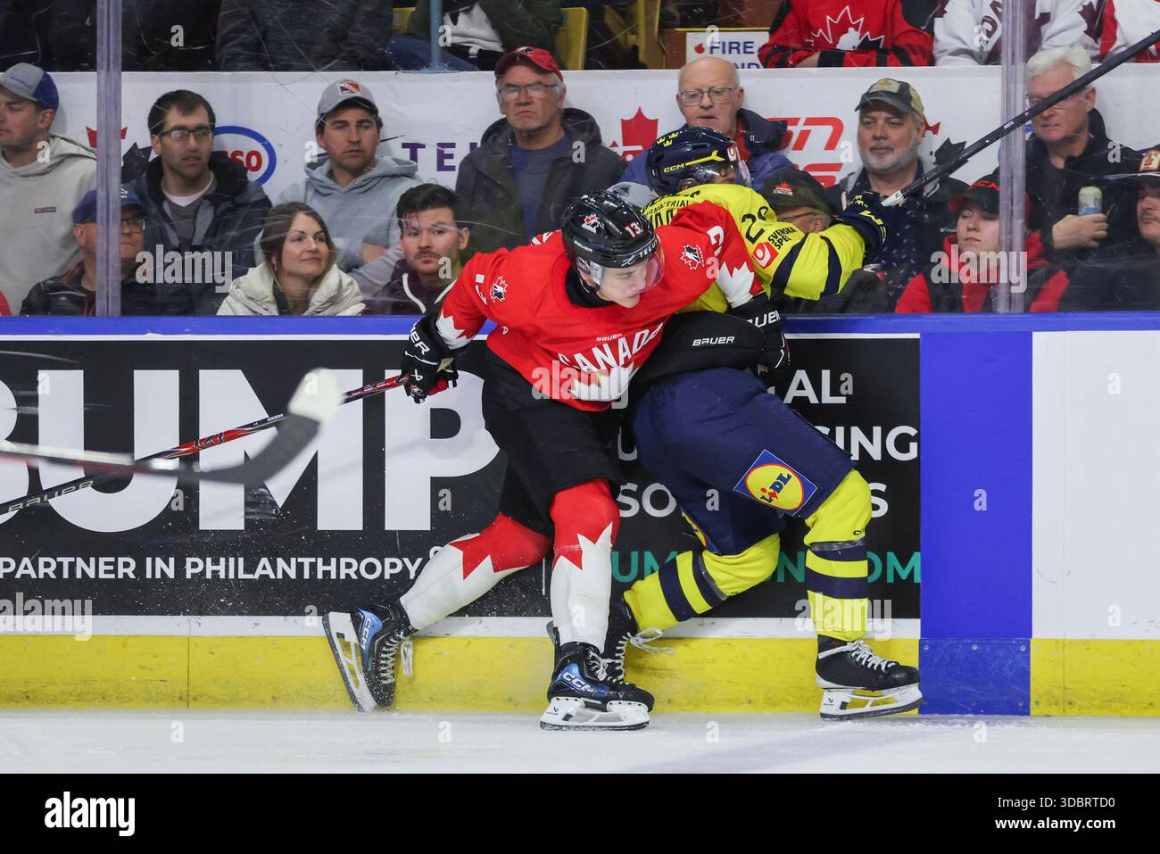 Canada's Ethan Mackenzie (13) hits Sweden's Casper Juustovaara Karlsson (29) during third period ...