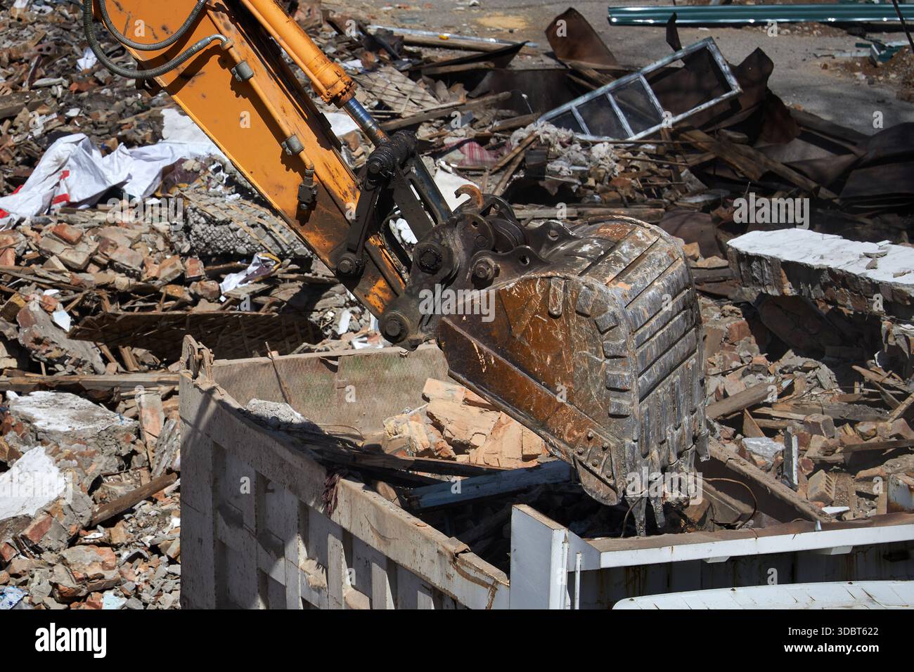 Excavator bucket loading debris into a dump truck, illustrating ...