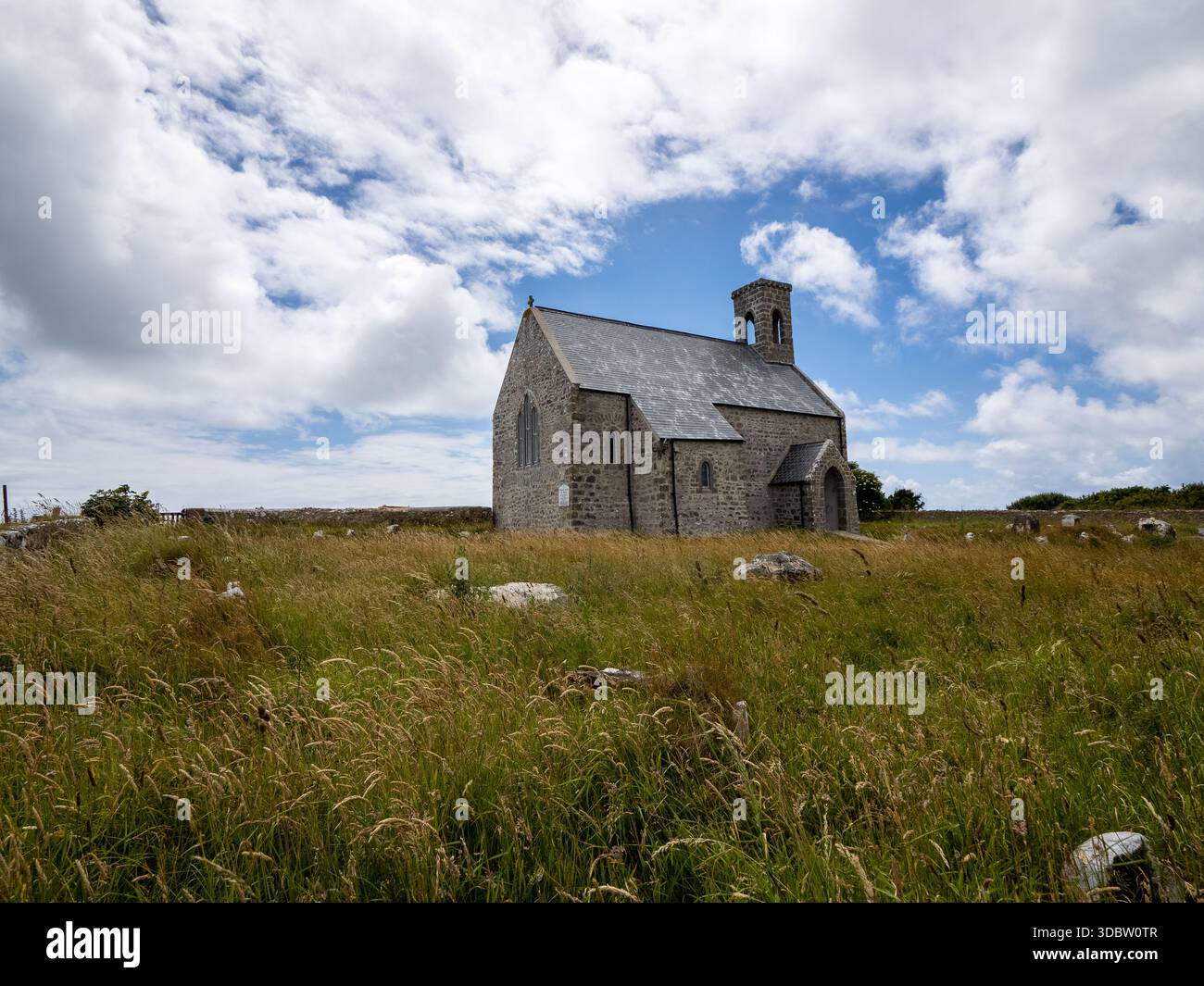 Stone country church in a wild grassy meadow under a dramatic cloudy ...