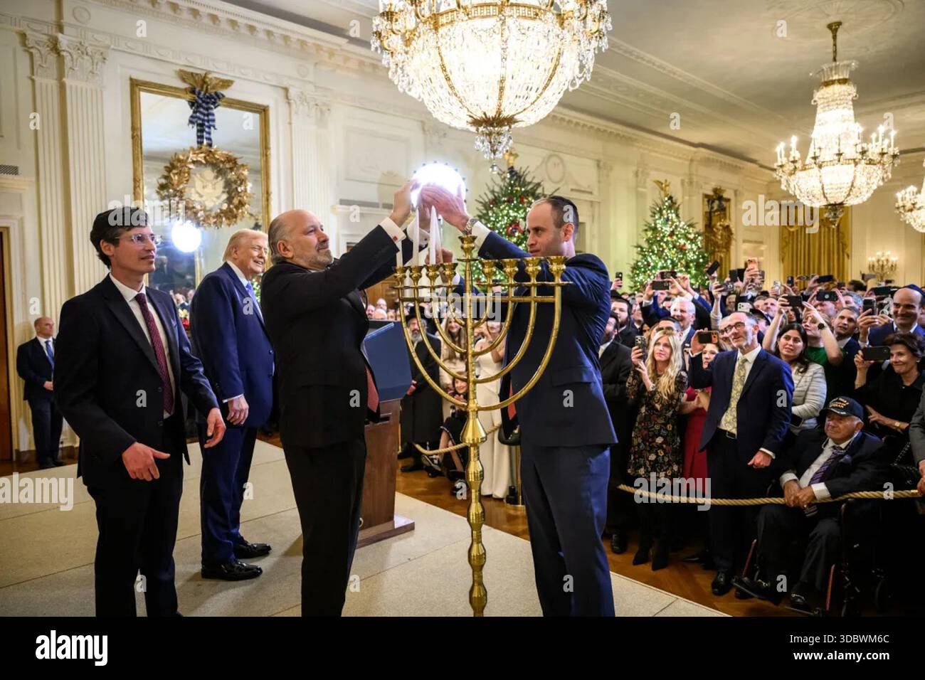 Guests observe the lighting of a Hanukkah menorah as President Donald ...
