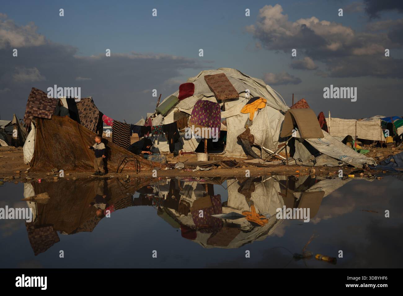 FILE - A tent is reflected in water at a makeshift camp for displaced ...