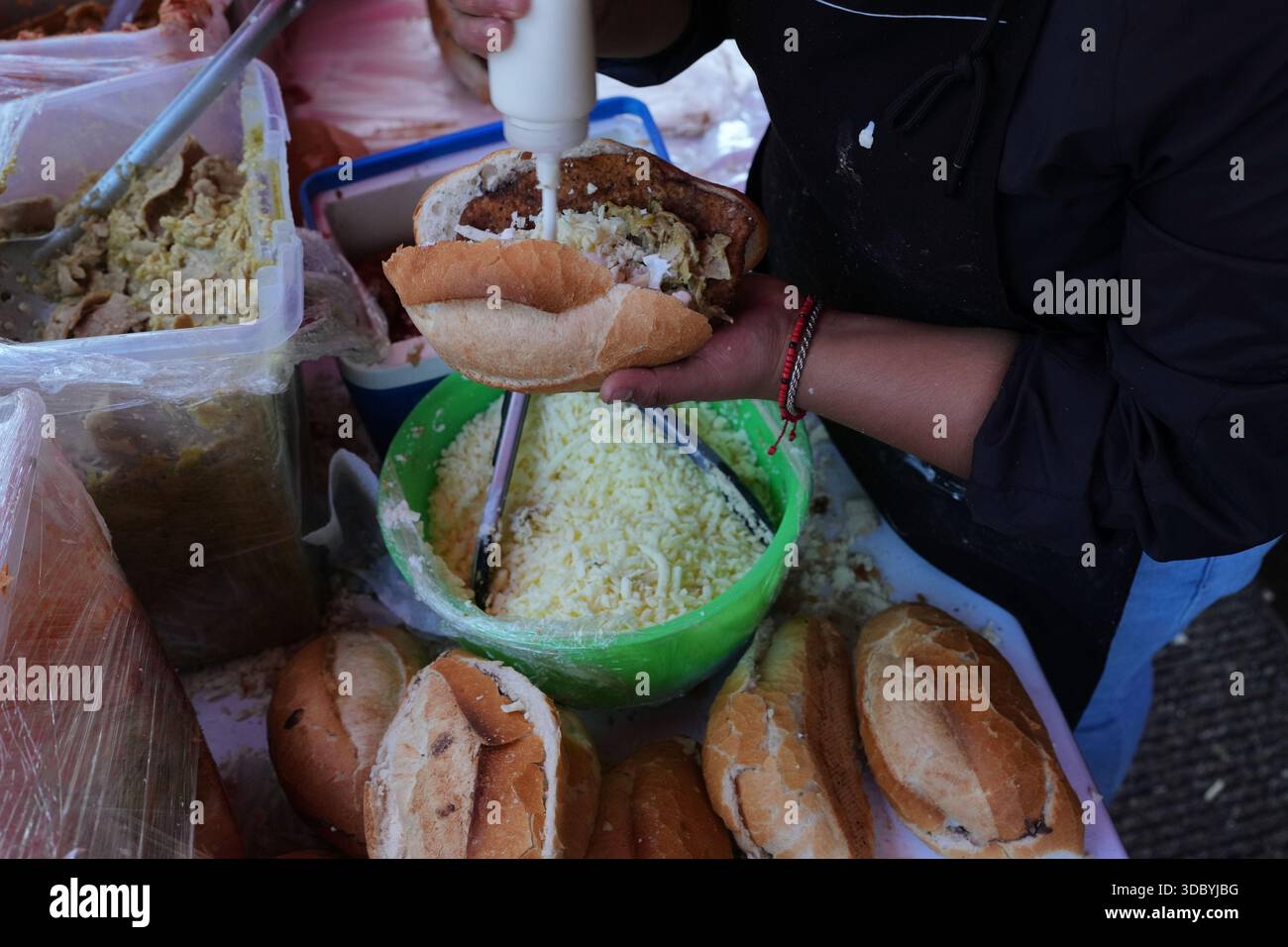 A vendor prepares a bolillo, a traditional Mexican bread, for ...