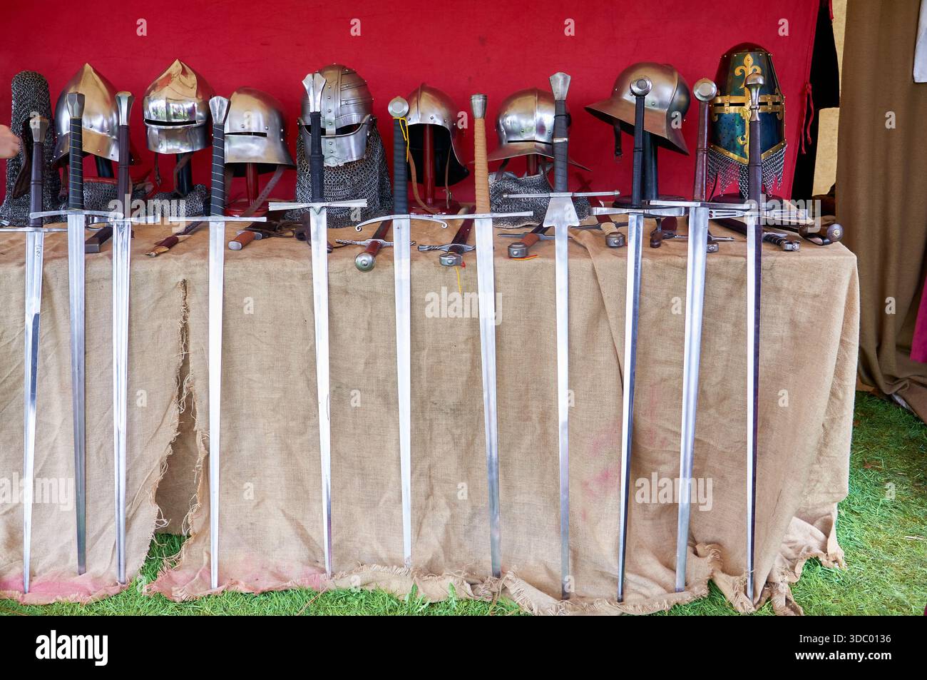 Medieval swords helmets and knight armor displayed upright on a table ...