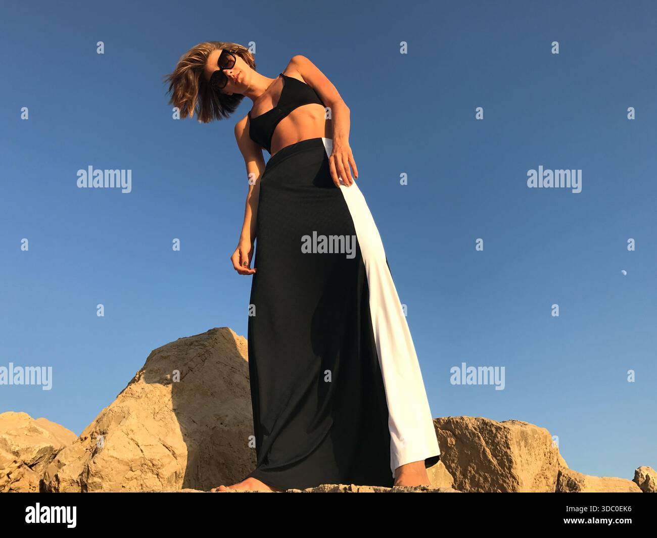 A stylish woman in long skirt and matching bra photographed from a low ...