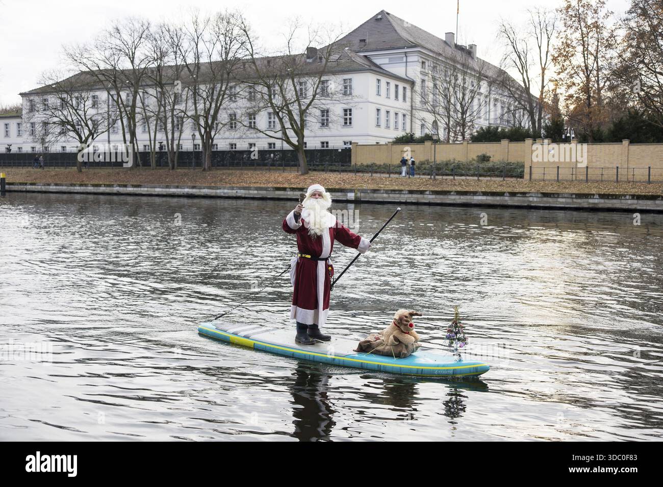 A water sports enthusiast dressed up as Santa Claus rides a SUP on the ...