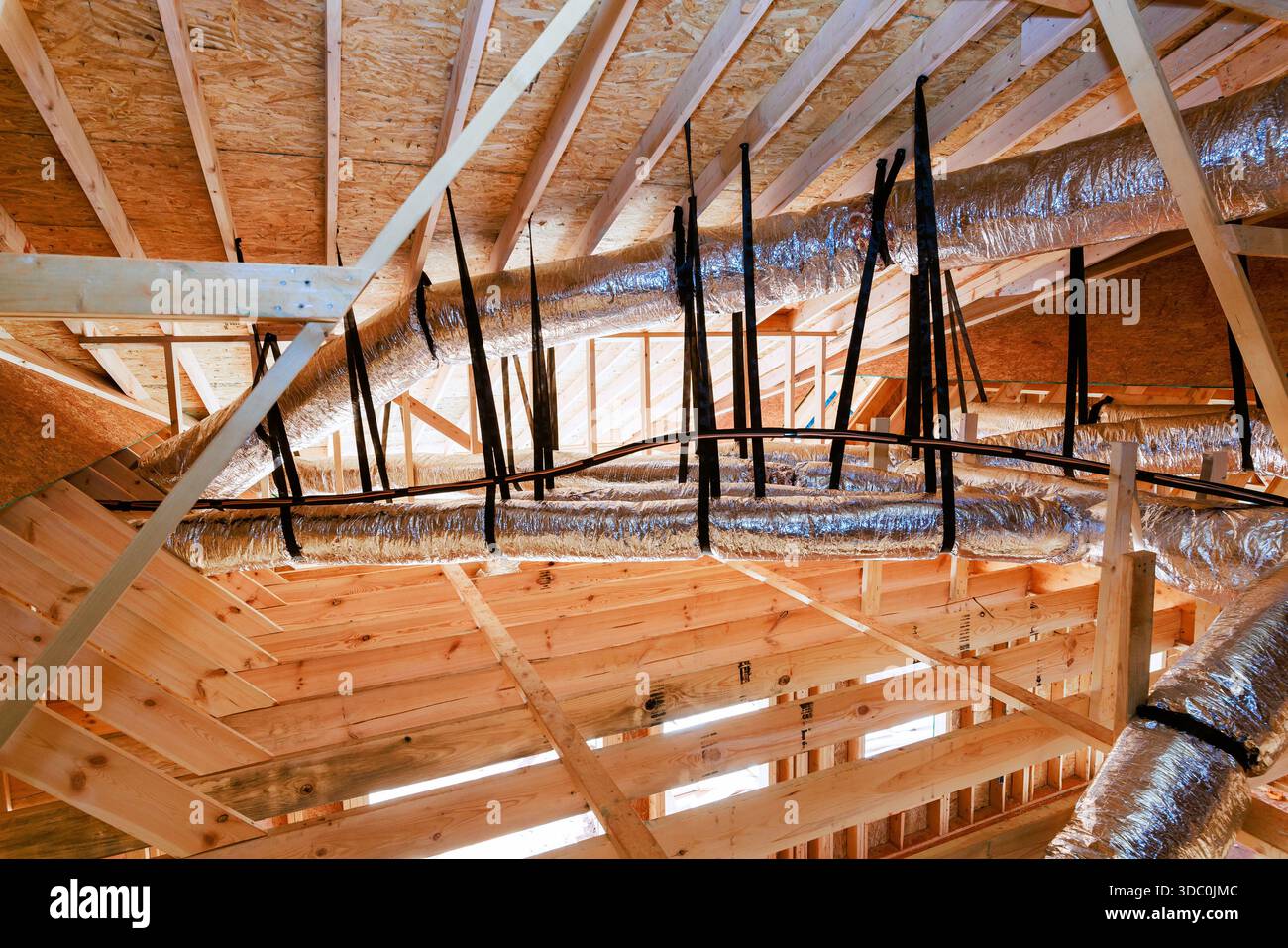 Workers install metal ducts in building under construction with wooden ...