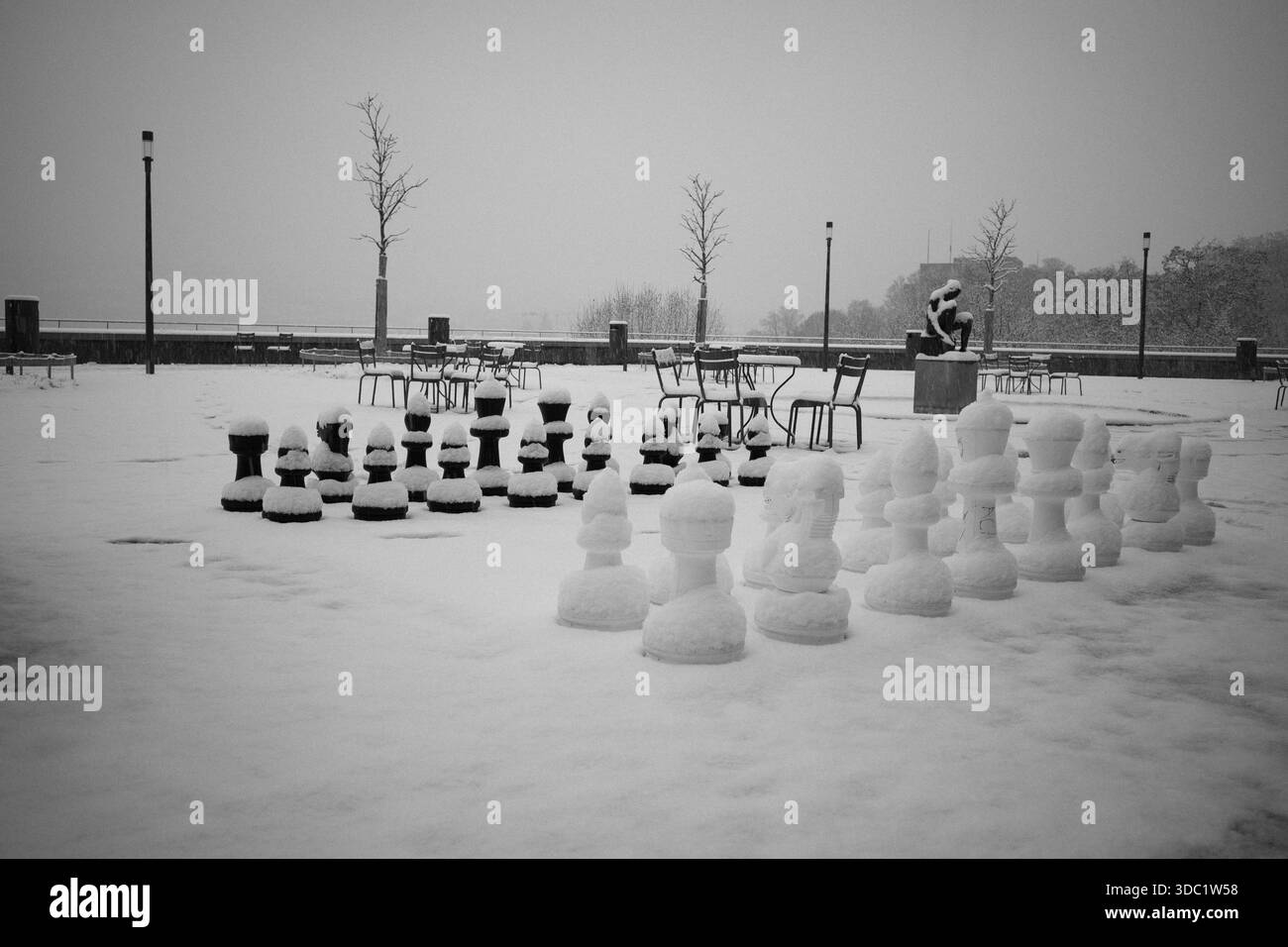 Snow-Covered Giant Chess Set and Empty Café Seating on Urban Plaza in ...