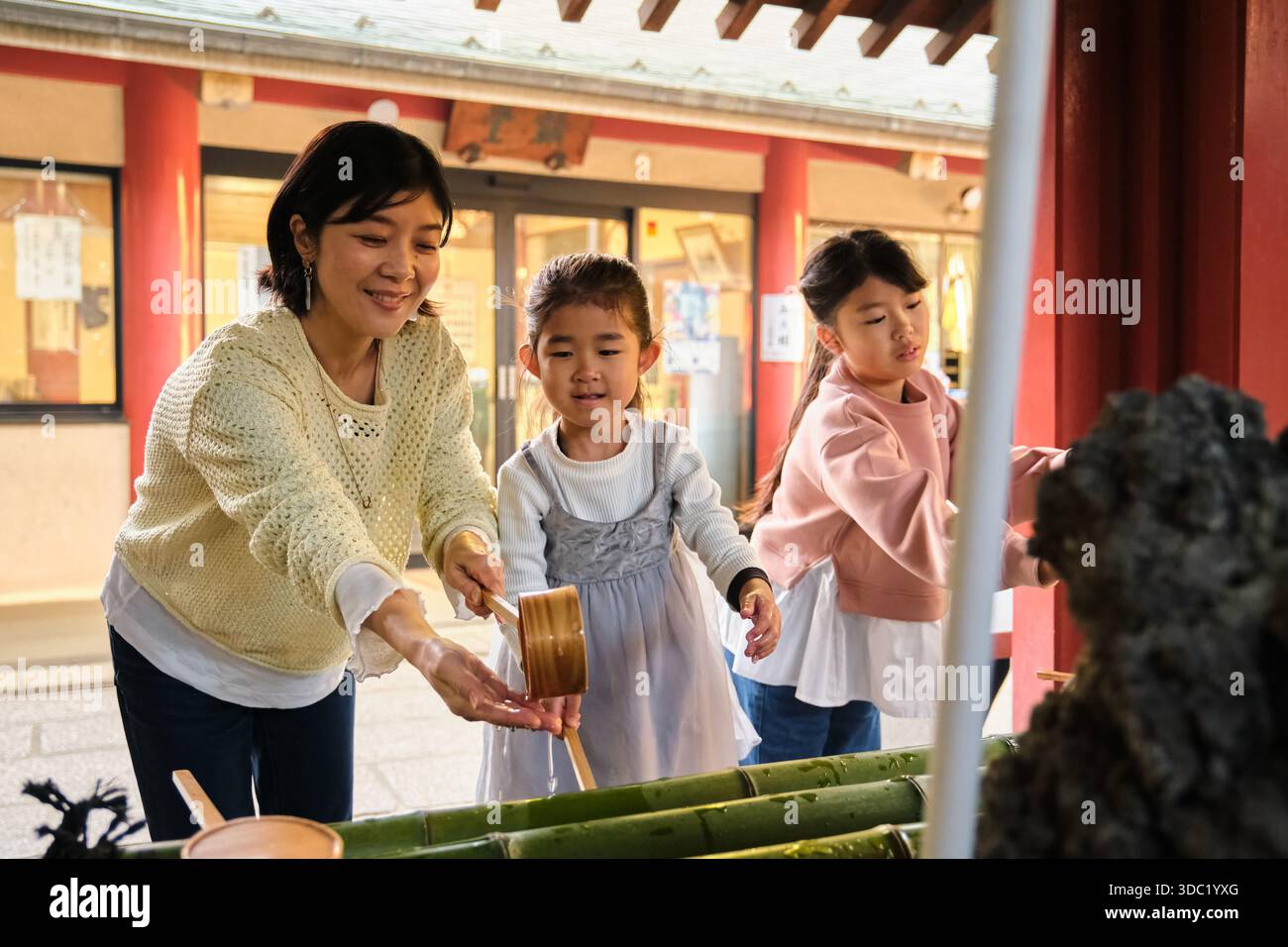 Japanese mother and daughters performing temple purification ritual ...