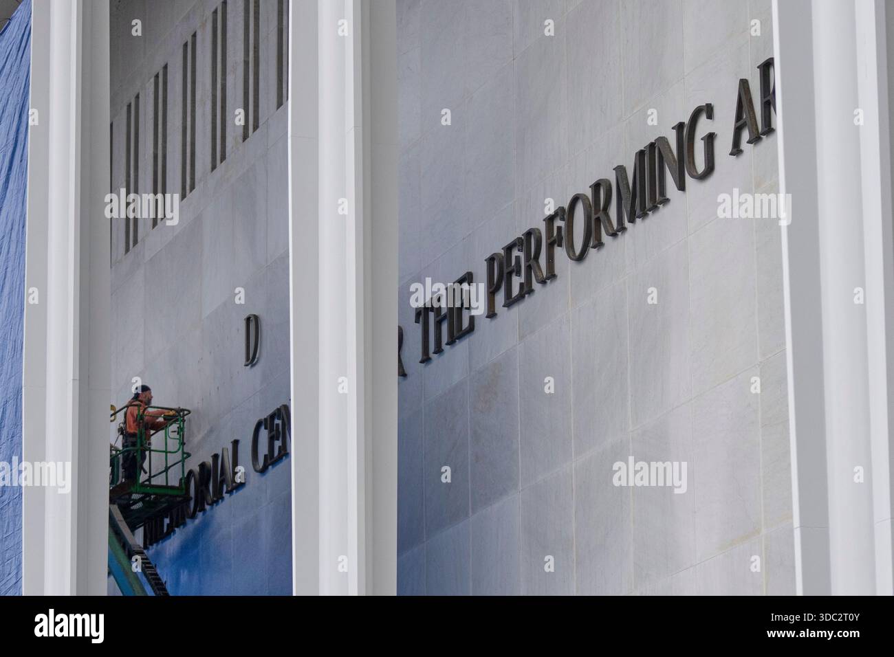 A worker drills holes near letters being installed above the signage on ...