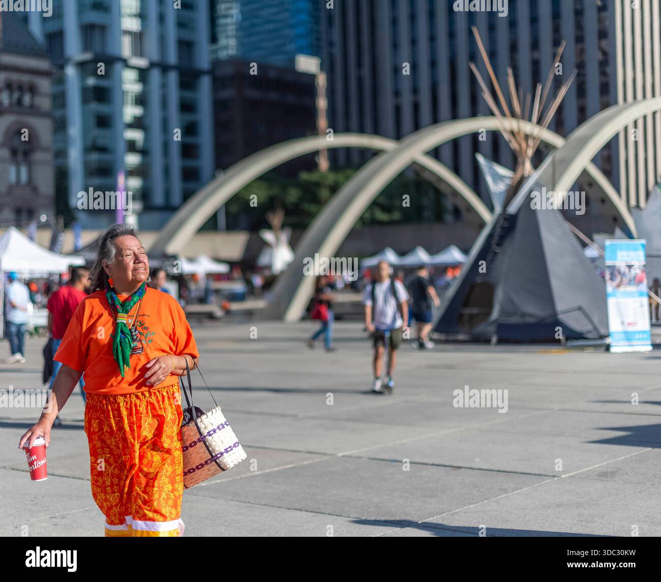 An indigenous woman walking in an orange outfit Stock Photo - Alamy