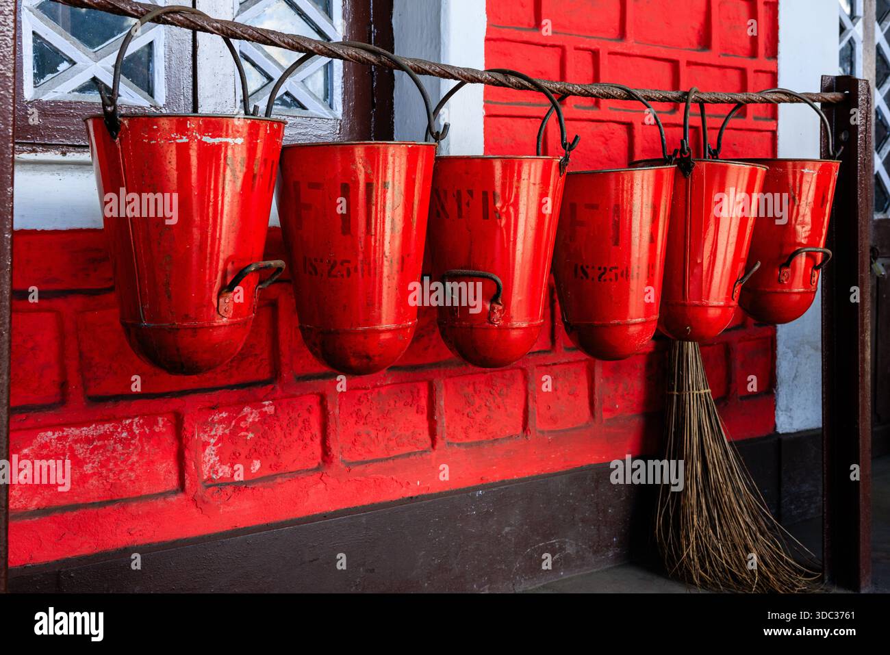six metal fire buckets hanging in a row from a metal wire with a rustic ...