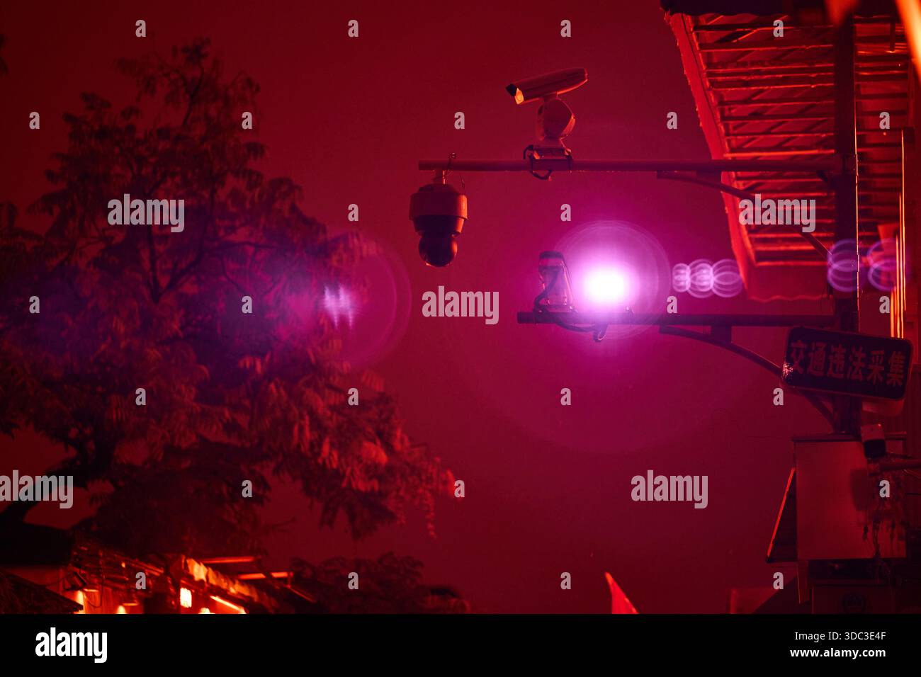 An infrared beam of light shines from a security camera watching over ...