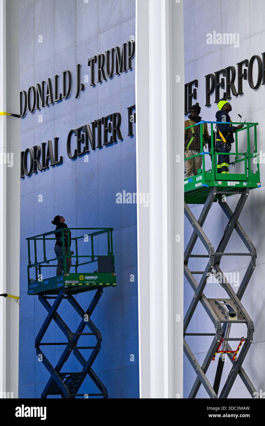 Workers install President Donald Trump’s name on the facade of the ...