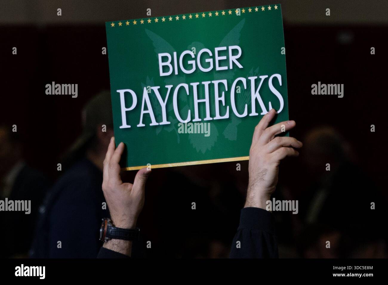 A person holds a “bigger paychecks” sign during President Donald Trump ...