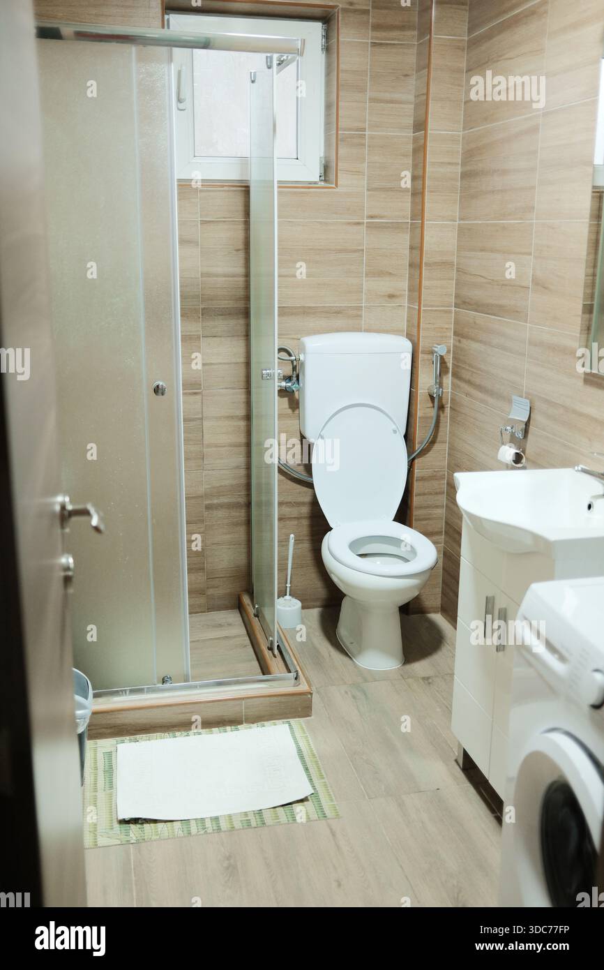 Modern compact bathroom with shower cabin, toilet and sink in neutral ...