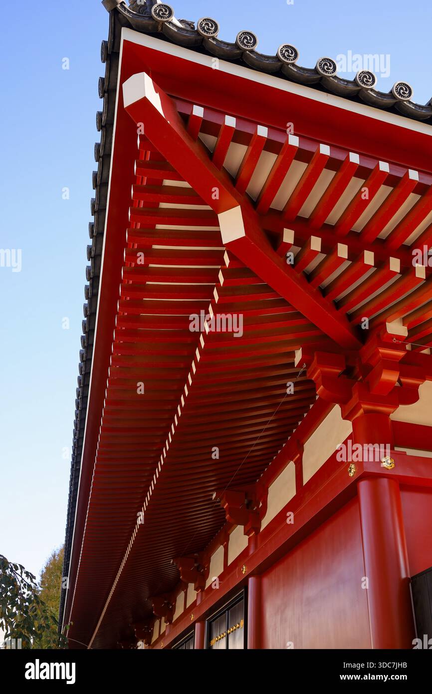 A bustling red Japanese temple tower rises beside a modern city ...