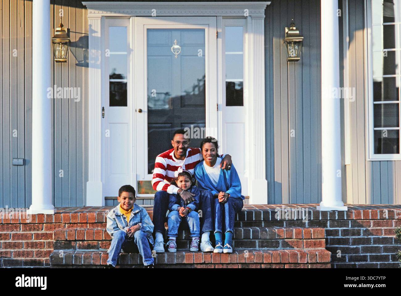 Four family members enjoy time together on the front steps of a ...