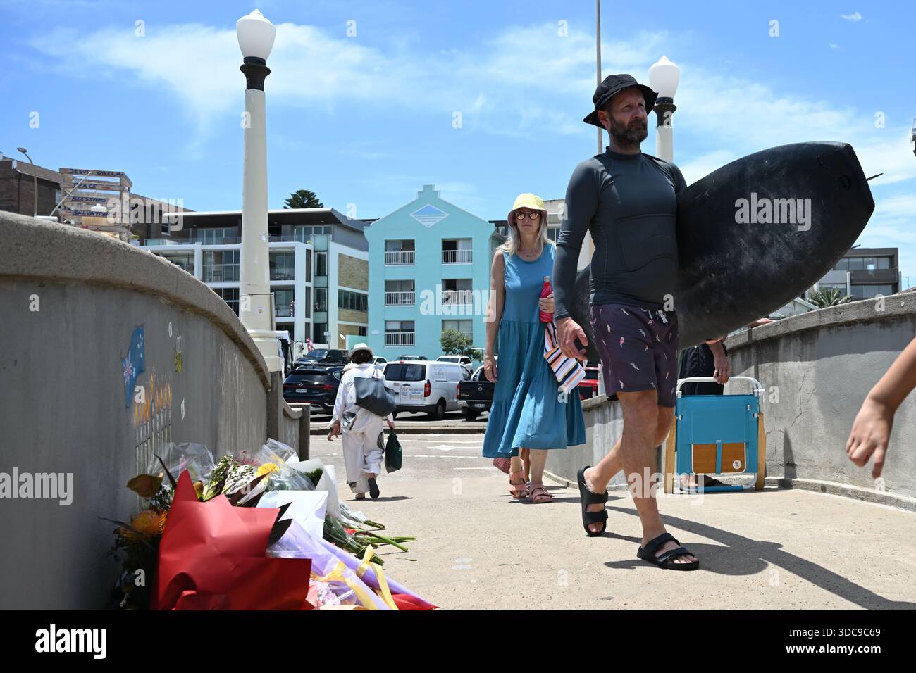 A surfer walks over the pedestrian bridge used by two gunmen as crowds ...
