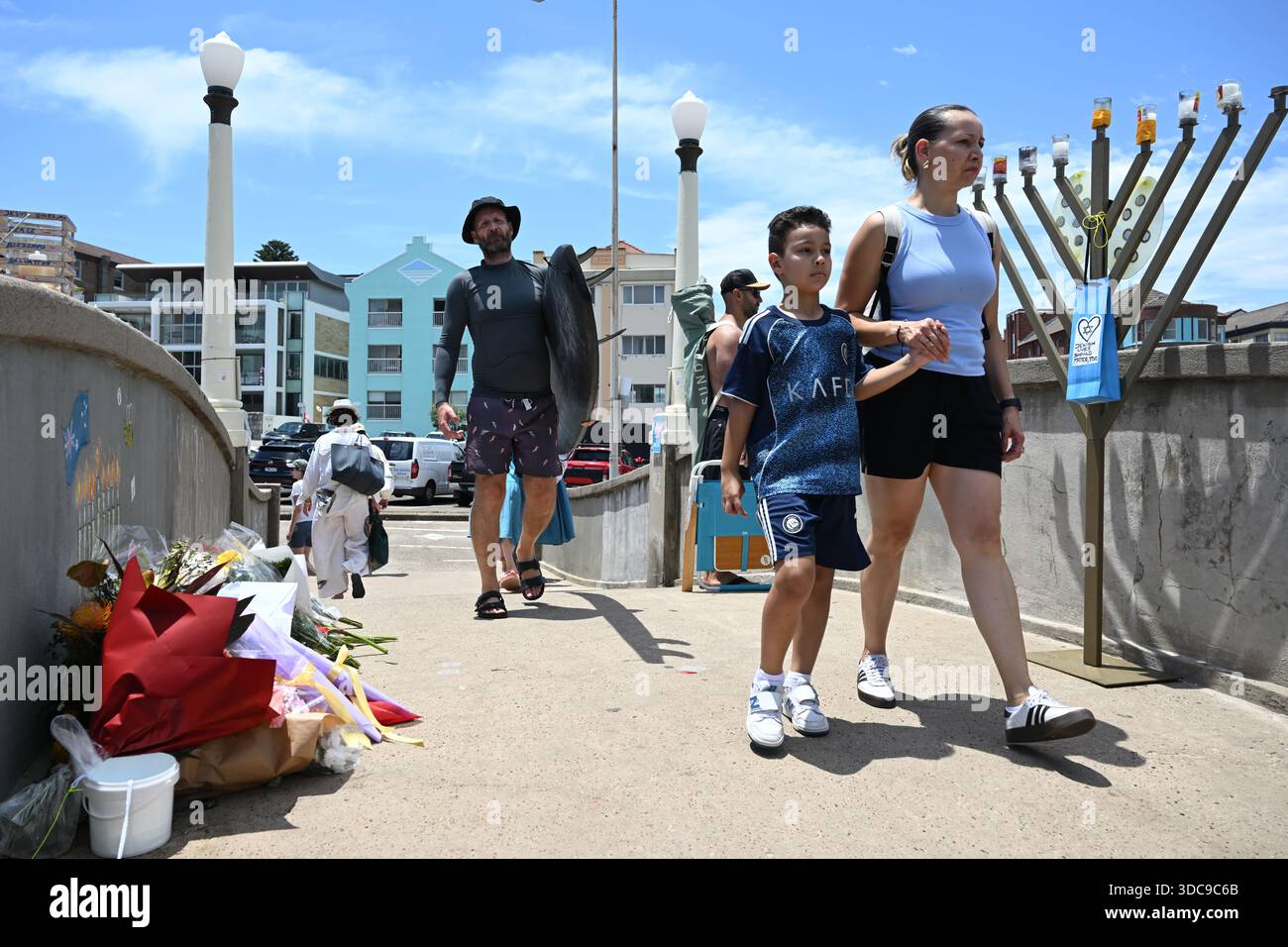 A surfer walks over the pedestrian bridge used by two gunmen as crowds ...