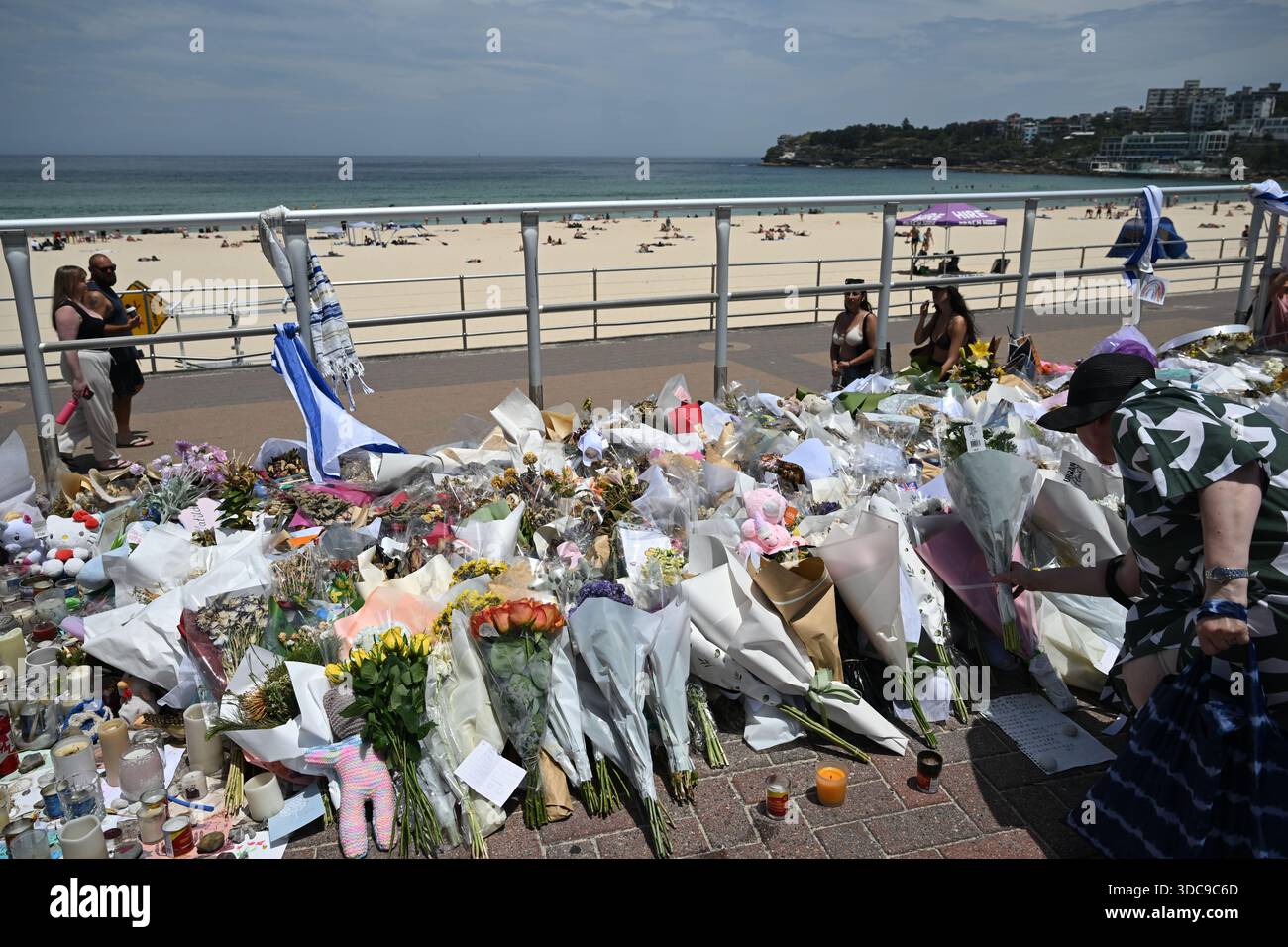 People continue to bring flowers to the Bondi Beach promenade as crowds ...