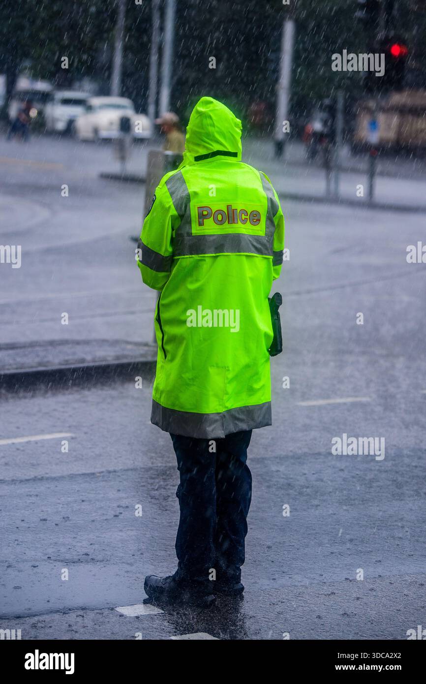 A Victoria Police officer stands in the rain near Parliament House ...