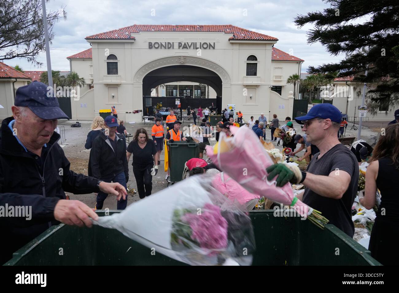 Workers gather floral tributes, messages of support and items left as a ...