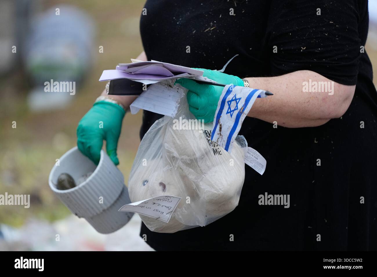 A worker gathers messages of support and items left as a memorial in ...