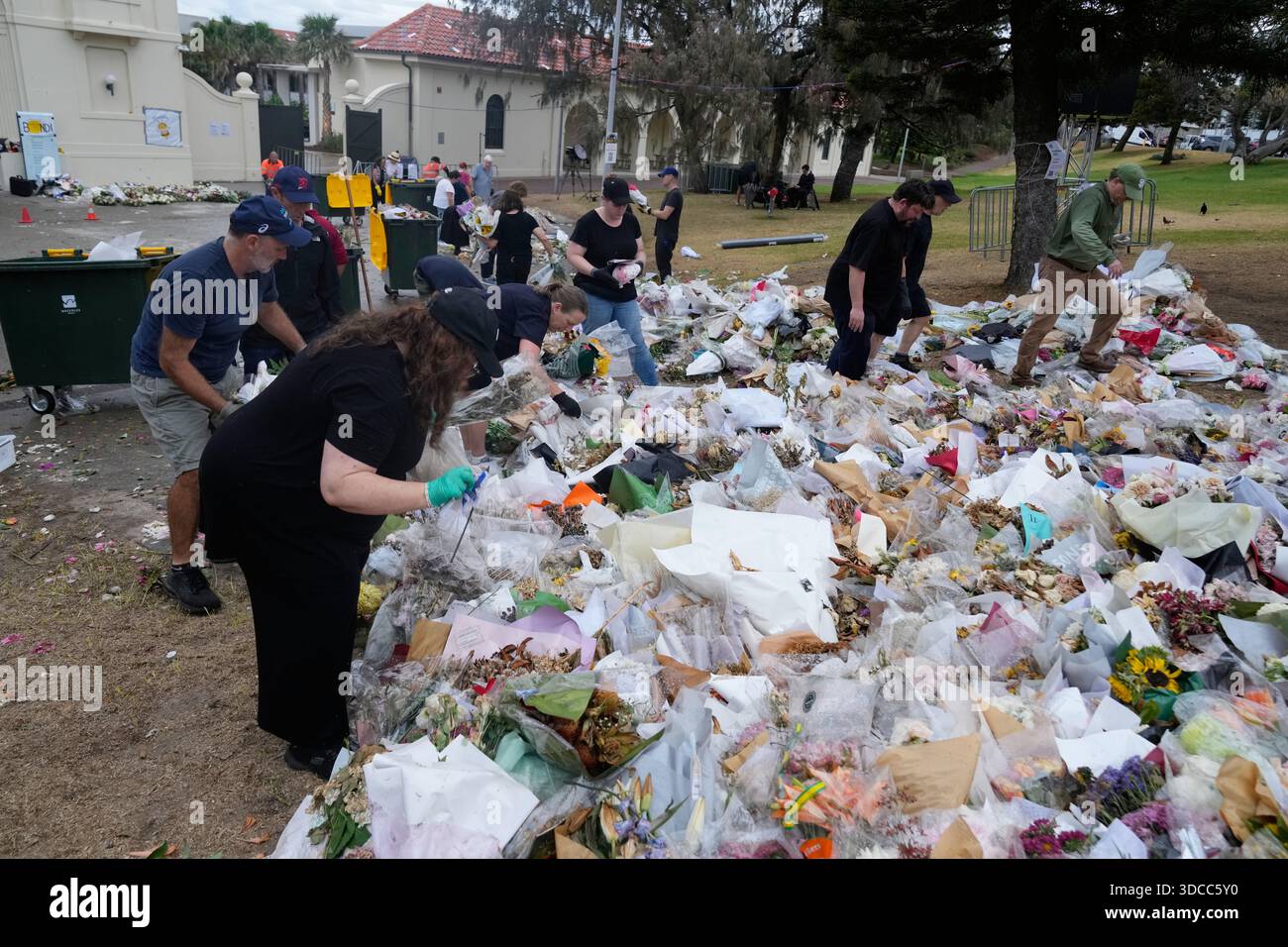 Workers gather floral tributes, messages of support and items left as a ...