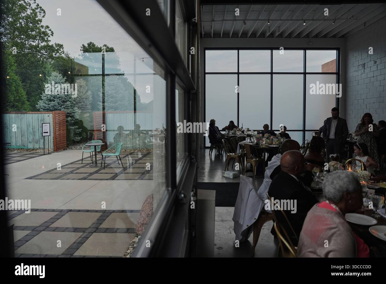 FILE - Guests sit inside during cocktail hour as empty chairs sit ...
