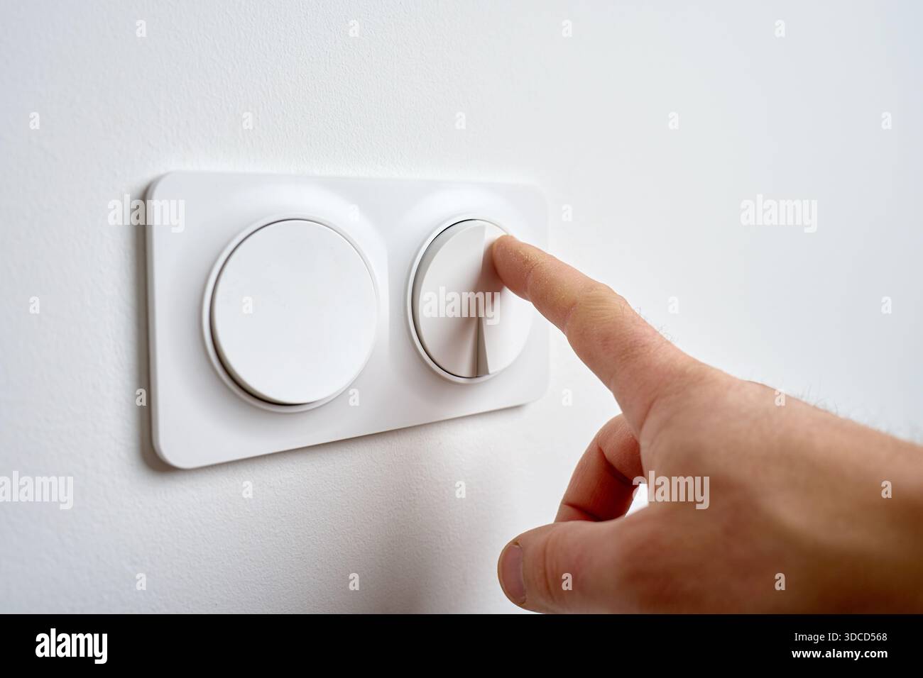 Close-up of hand pressing modern white wall light switch on interior ...