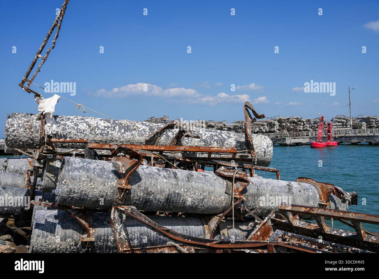 Rusty, barnacle-covered metal pipes at an abandoned harbor symbolize ...