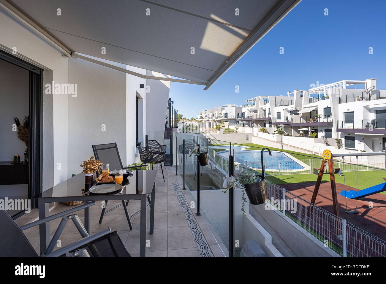 Elegant terrace with breakfast setup facing communal pool and children ...
