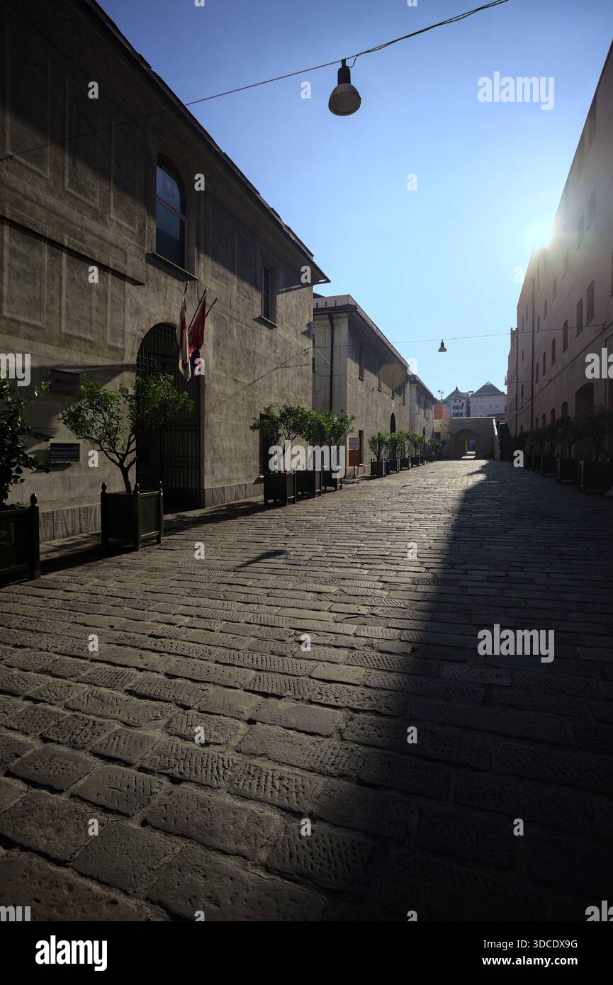 Stone paved alley counterlit by the sun between buildings with their ...