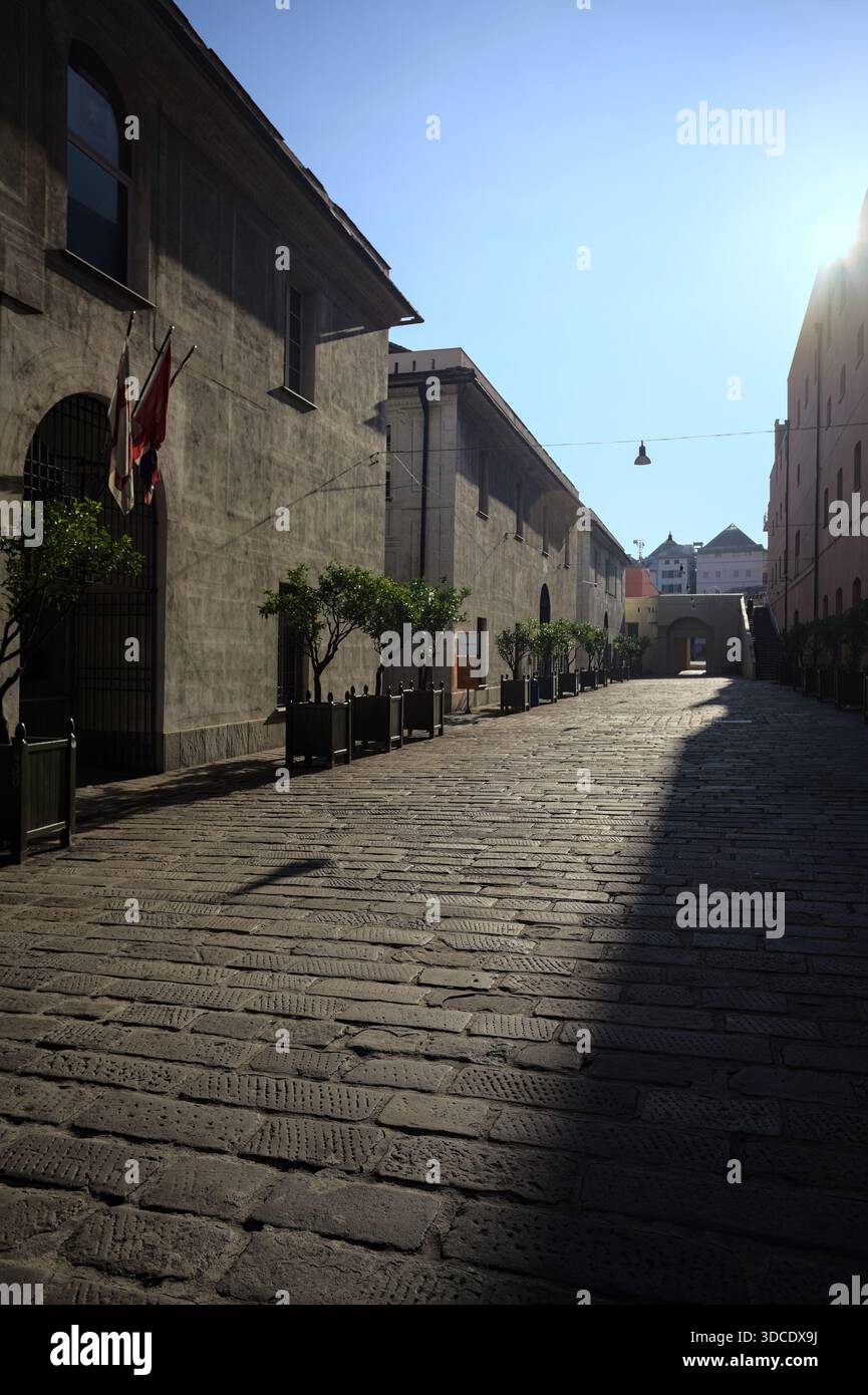 Stone paved alley counterlit by the sun between buildings with their ...
